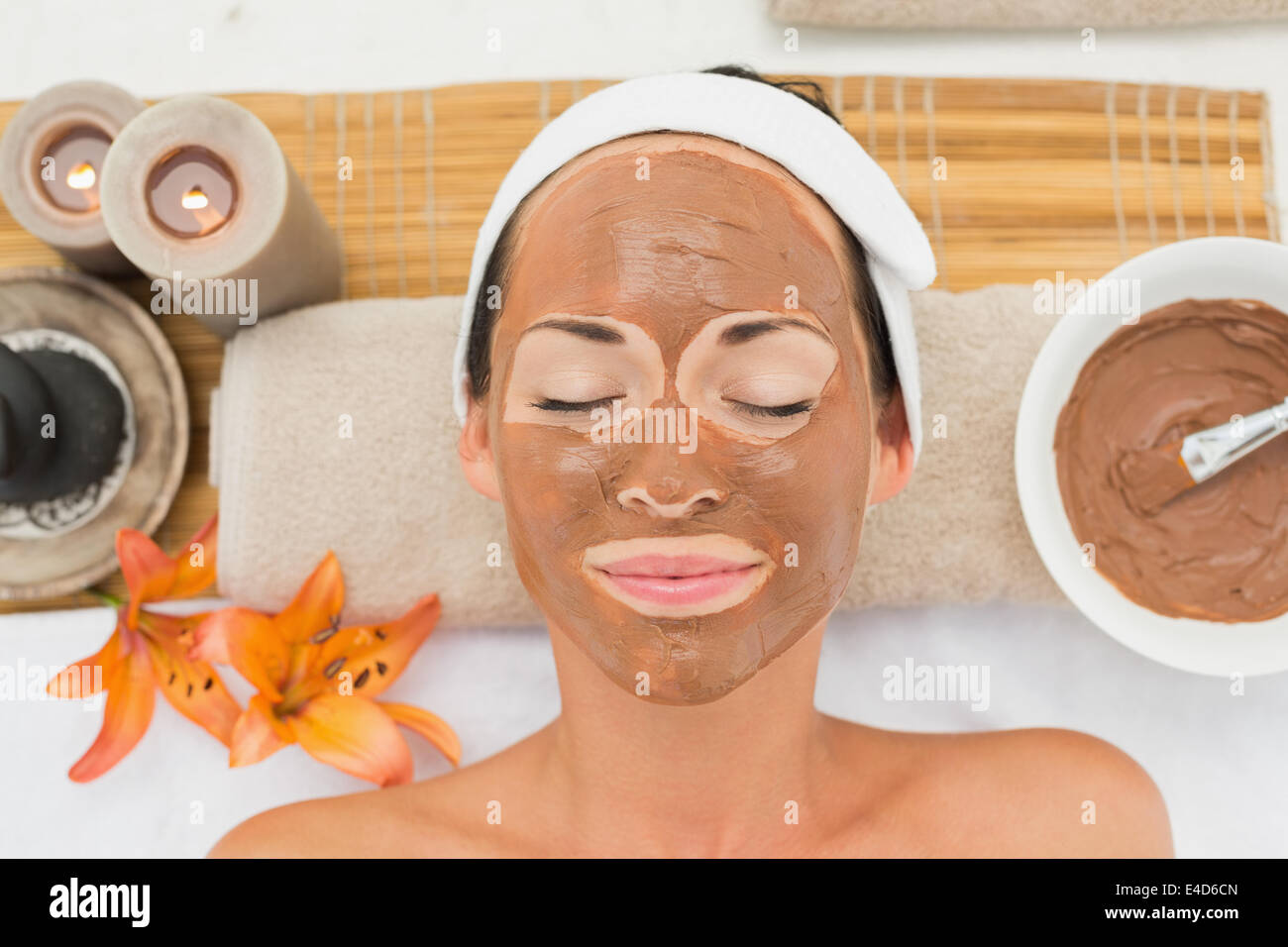 Smiling brunette getting a mud treatment facial Stock Photo - Alamy