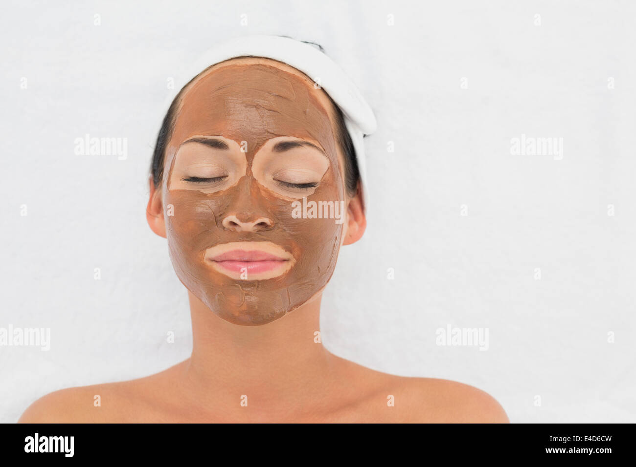 Smiling brunette getting a mud treatment facial Stock Photo - Alamy