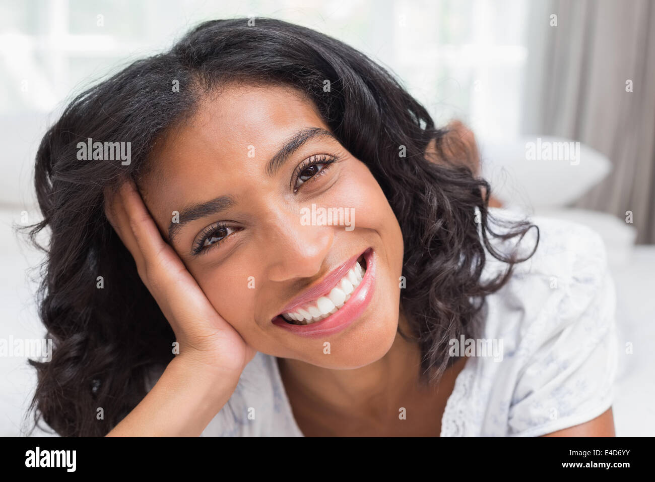 Pretty woman lying on bed smiling at camera Stock Photo - Alamy