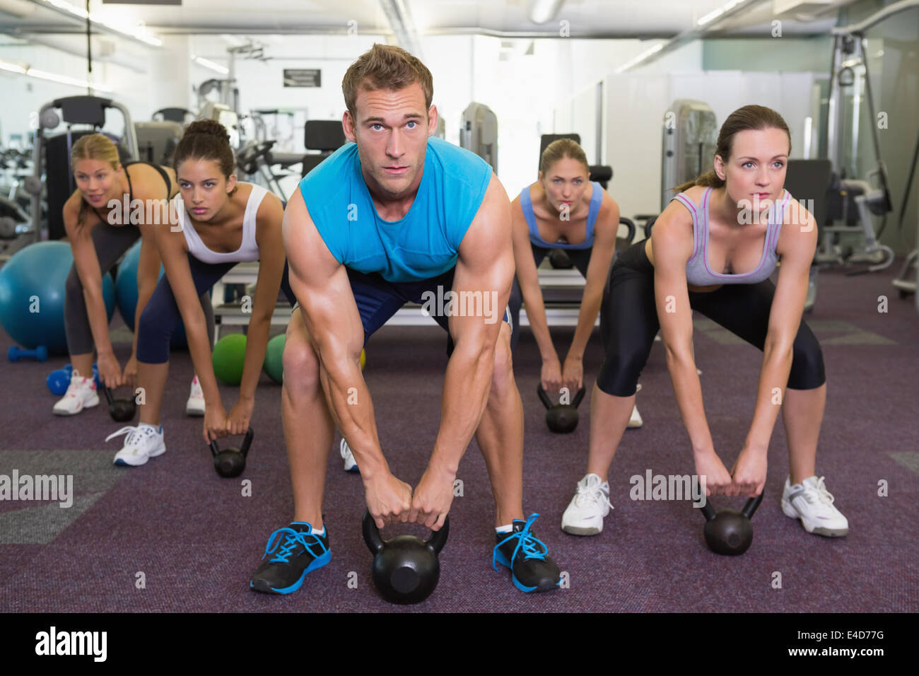 Muscular instructor leading kettlebell class Stock Photo - Alamy