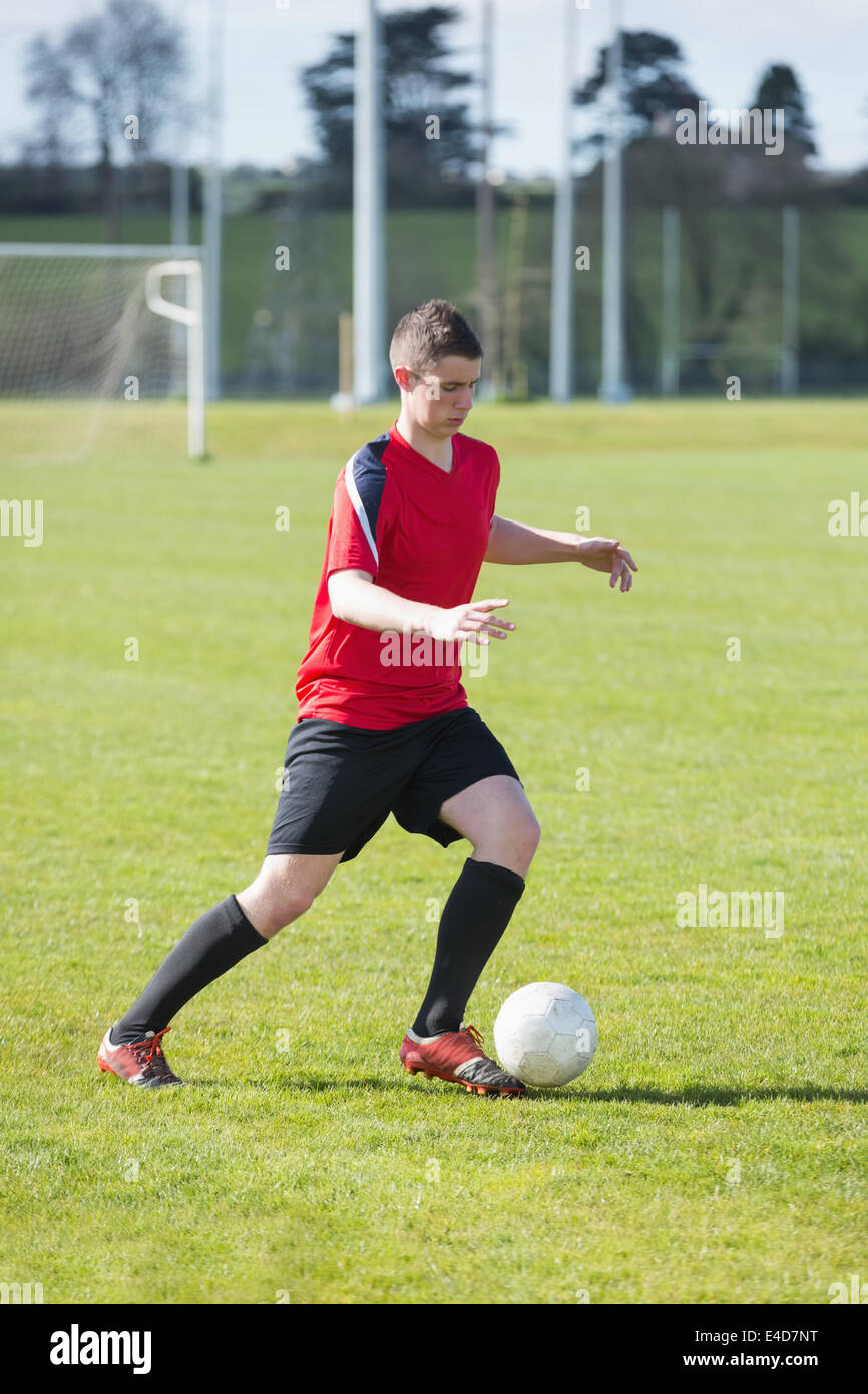 Football player in red playing on pitch Stock Photo - Alamy