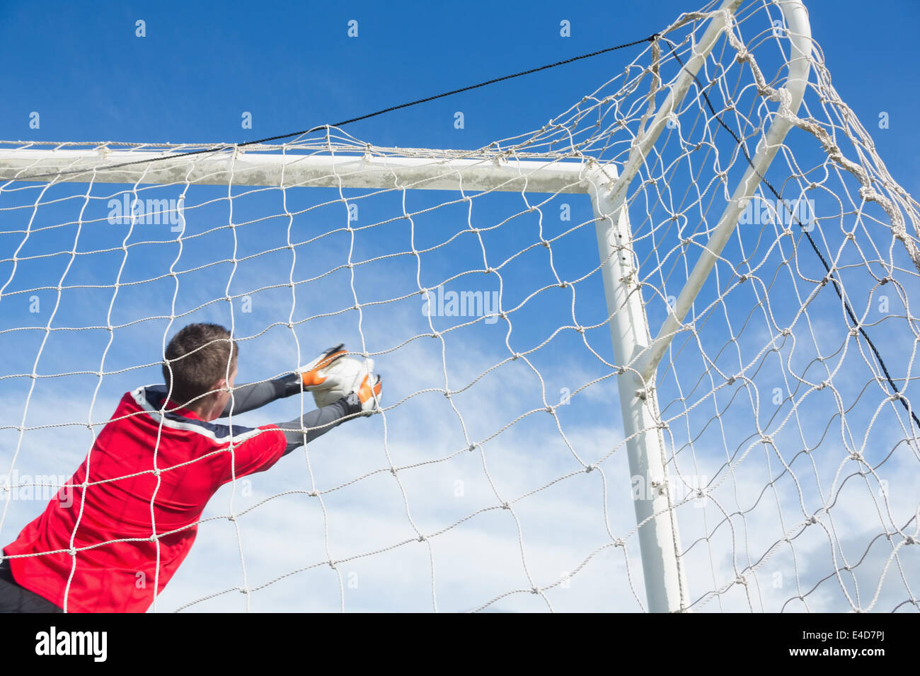 Goalkeeper in red making a save Stock Photo - Alamy