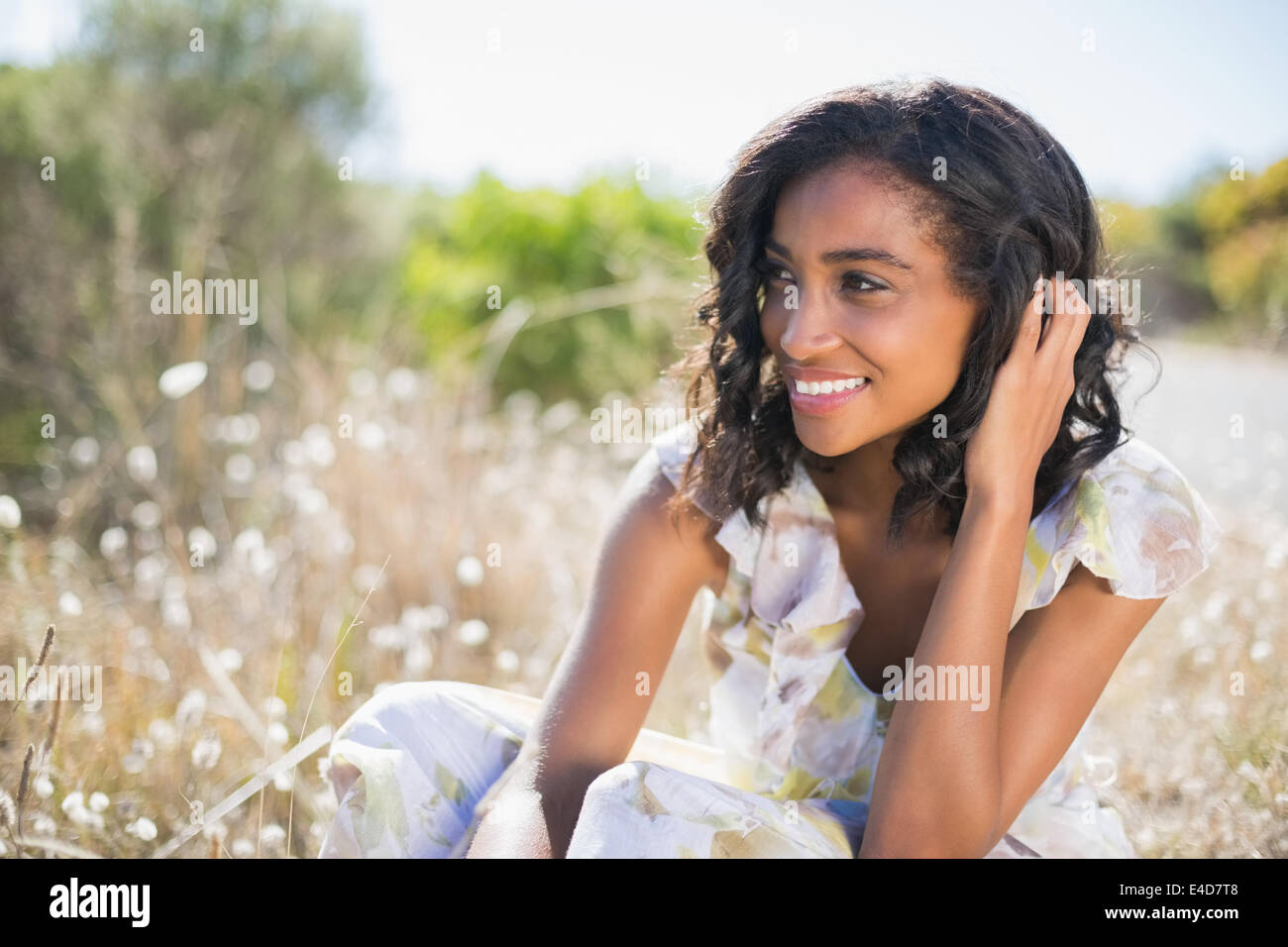 Happy pretty woman sitting on the grass in floral dress Stock Photo - Alamy