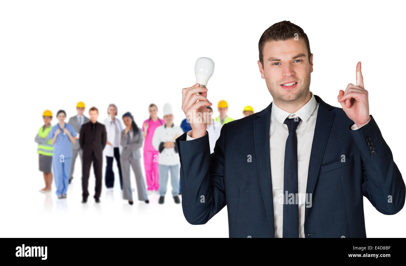 Composite image of businessman holding light bulb and pointing Stock ...