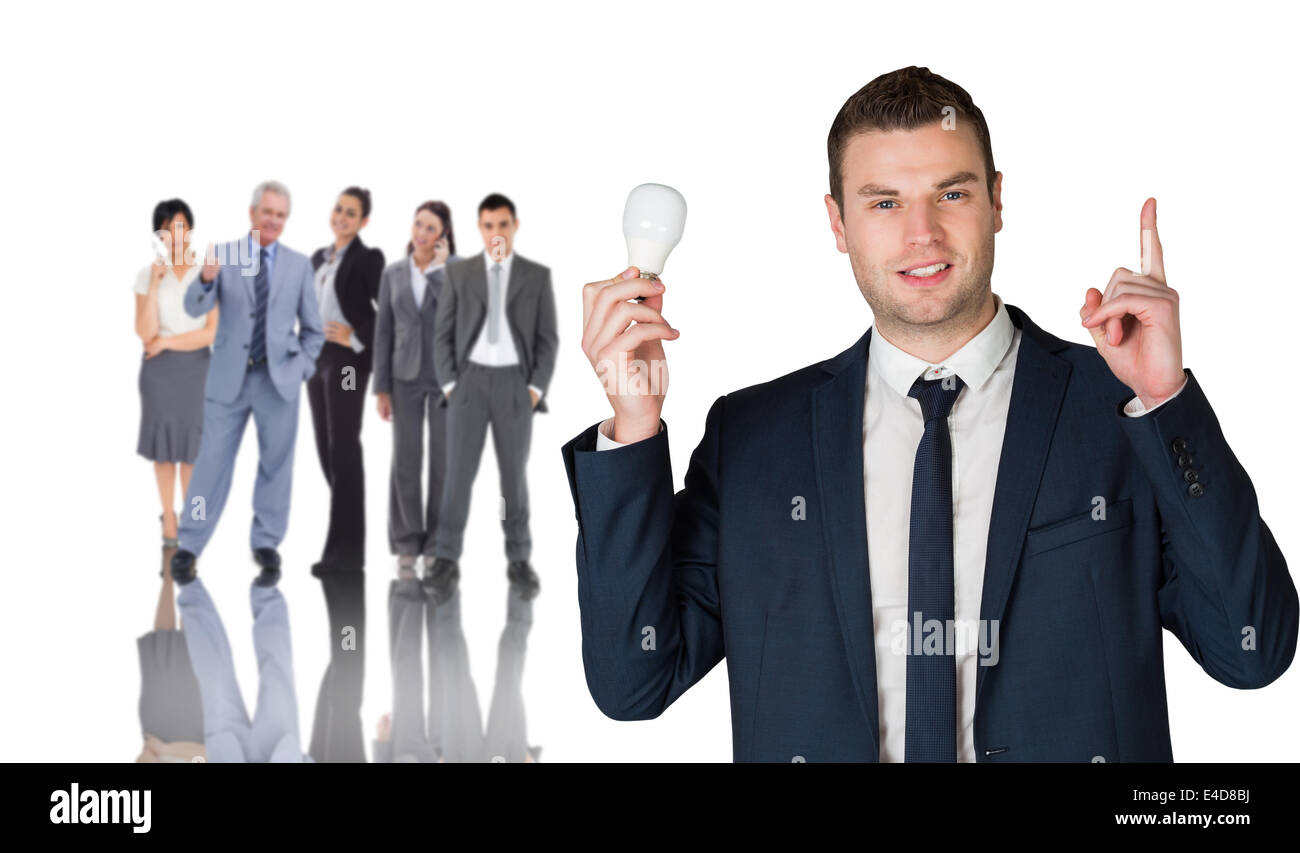 Composite image of businessman holding light bulb and pointing Stock ...