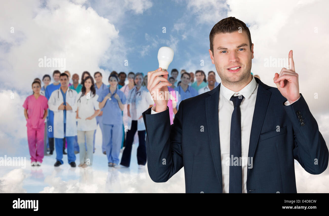 Composite image of businessman holding light bulb and pointing Stock ...