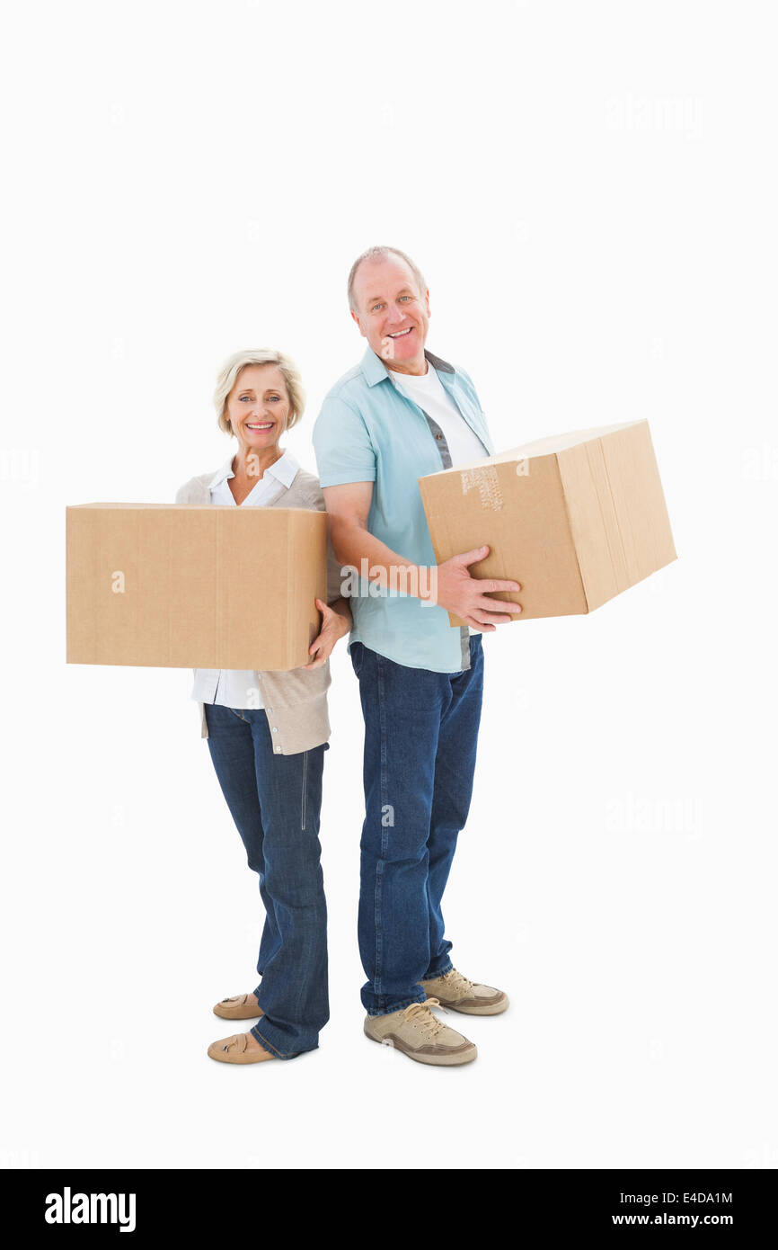 Older couple smiling at camera holding moving boxes Stock Photo - Alamy