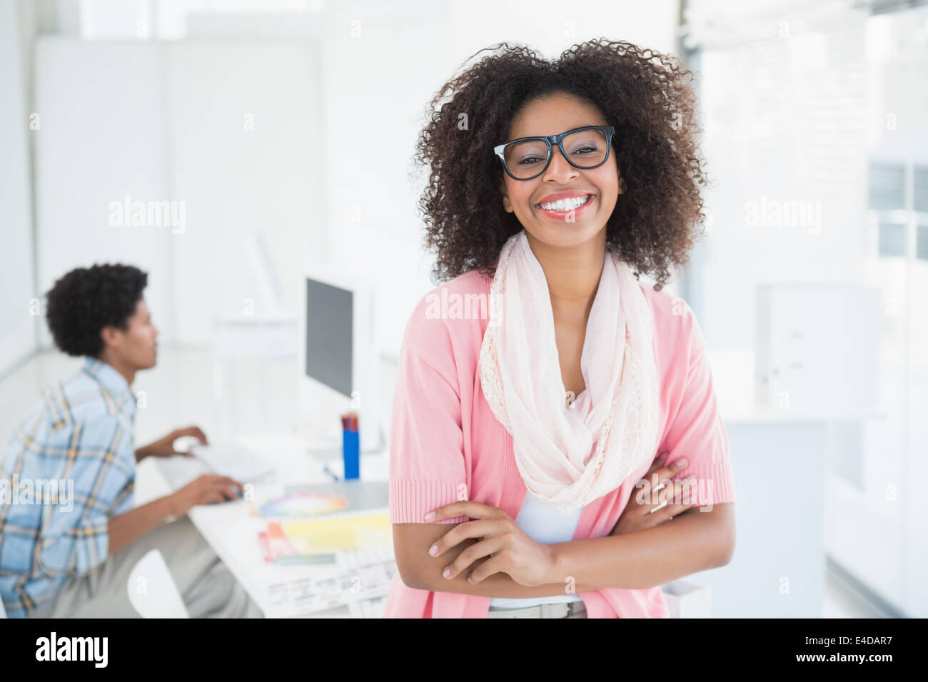 Young designer smiling at camera with colleague behind her Stock Photo ...