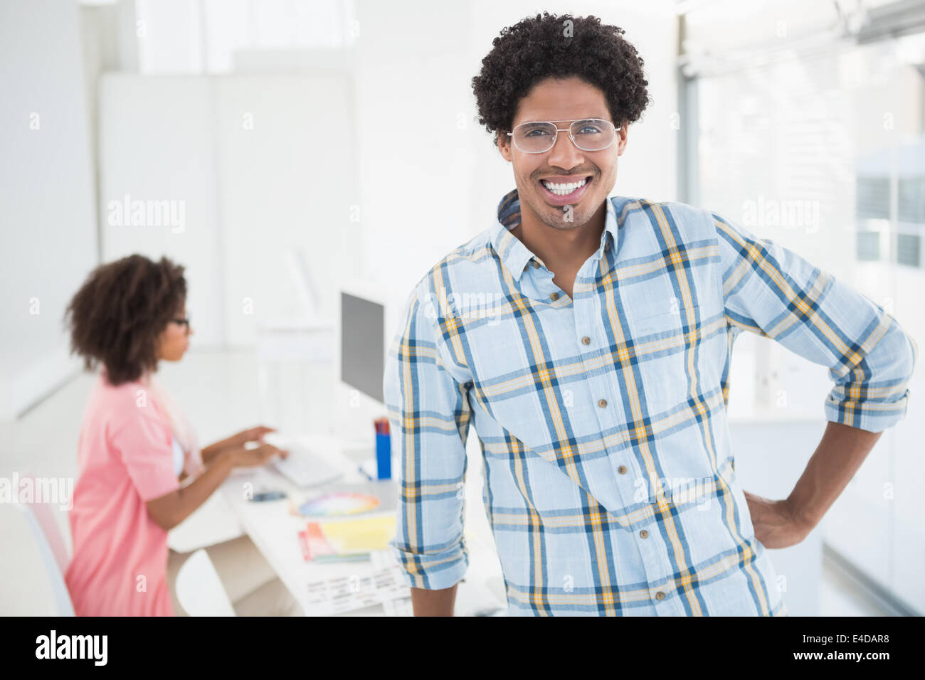 Young designer smiling at camera with colleague behind him Stock Photo ...