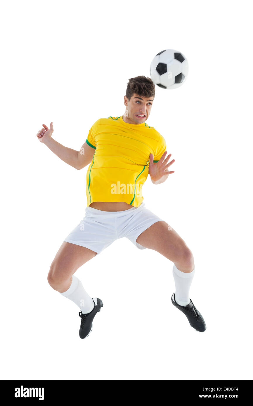 Football player in yellow jersey jumping to ball Stock Photo - Alamy