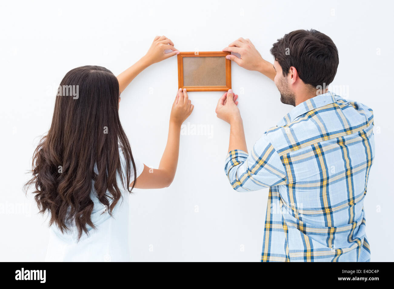 Happy young couple putting up picture frame Stock Photo - Alamy
