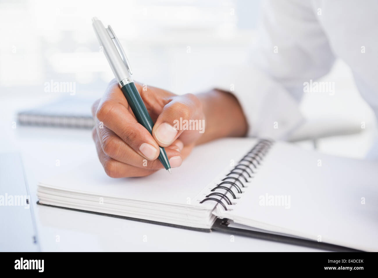 Businessman writing in notepad at desk Stock Photo - Alamy