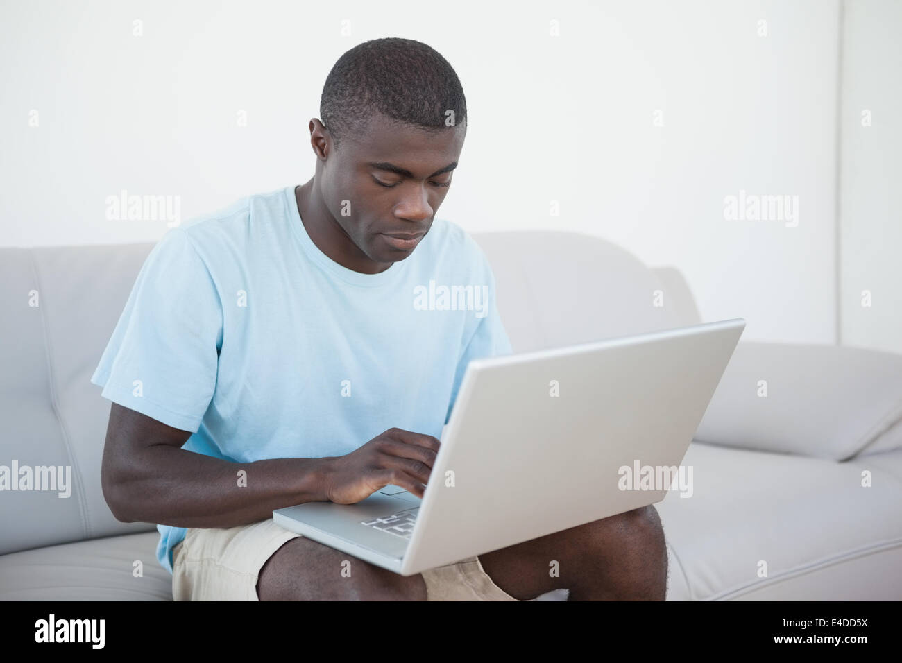 Casual man sitting on sofa using laptop Stock Photo - Alamy