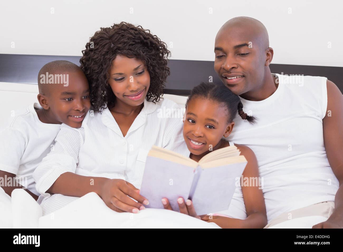 Happy family reading book together in bed Stock Photo - Alamy