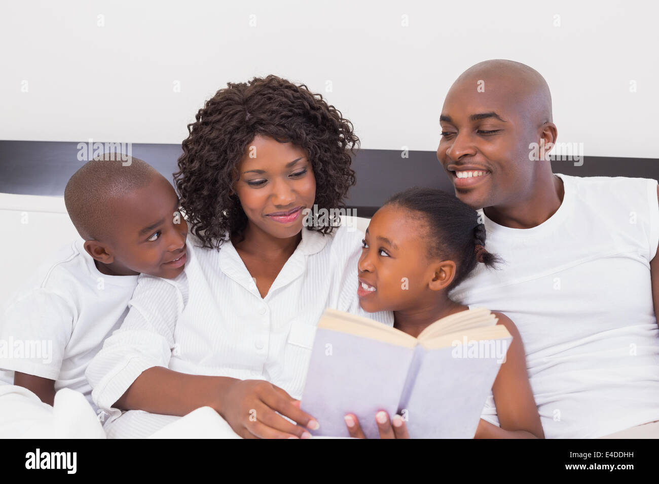Happy family reading book together in bed Stock Photo - Alamy