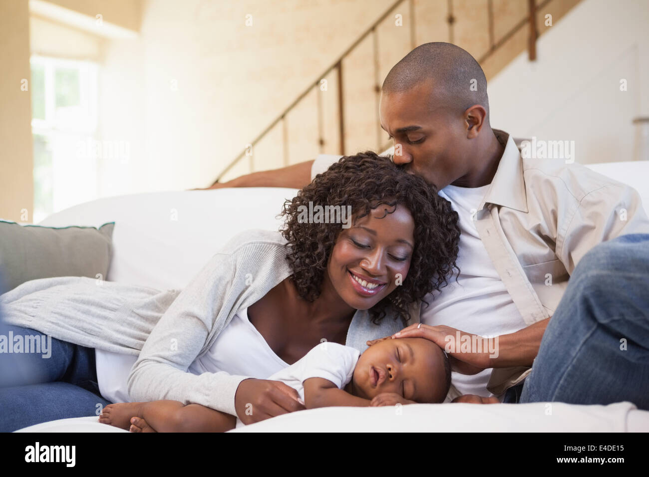 Baby boy sleeping peacefully on couch with happy parents Stock Photo ...