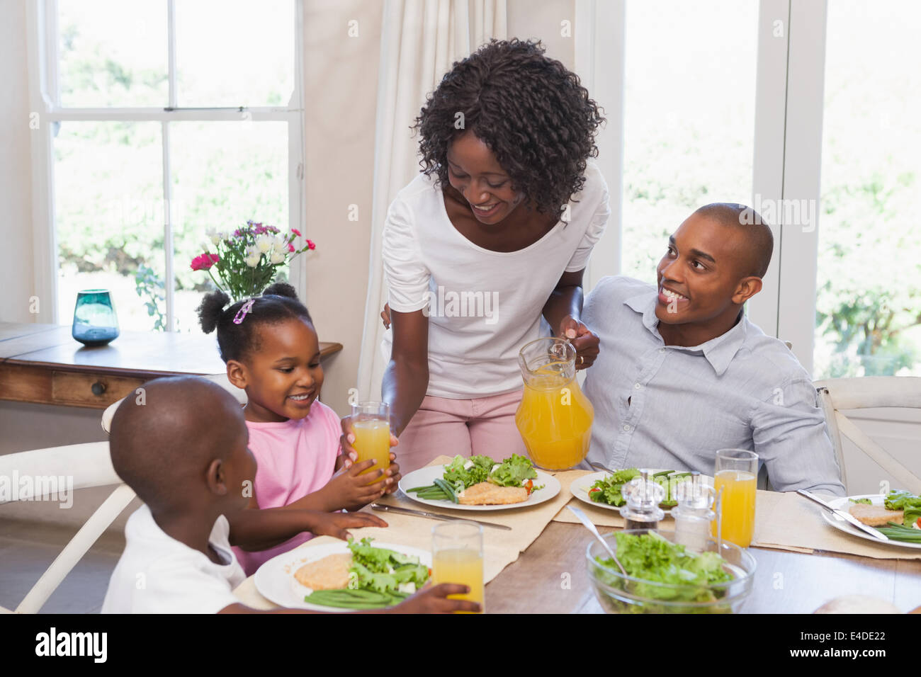 Mother serving juice to her family at lunch Stock Photo - Alamy