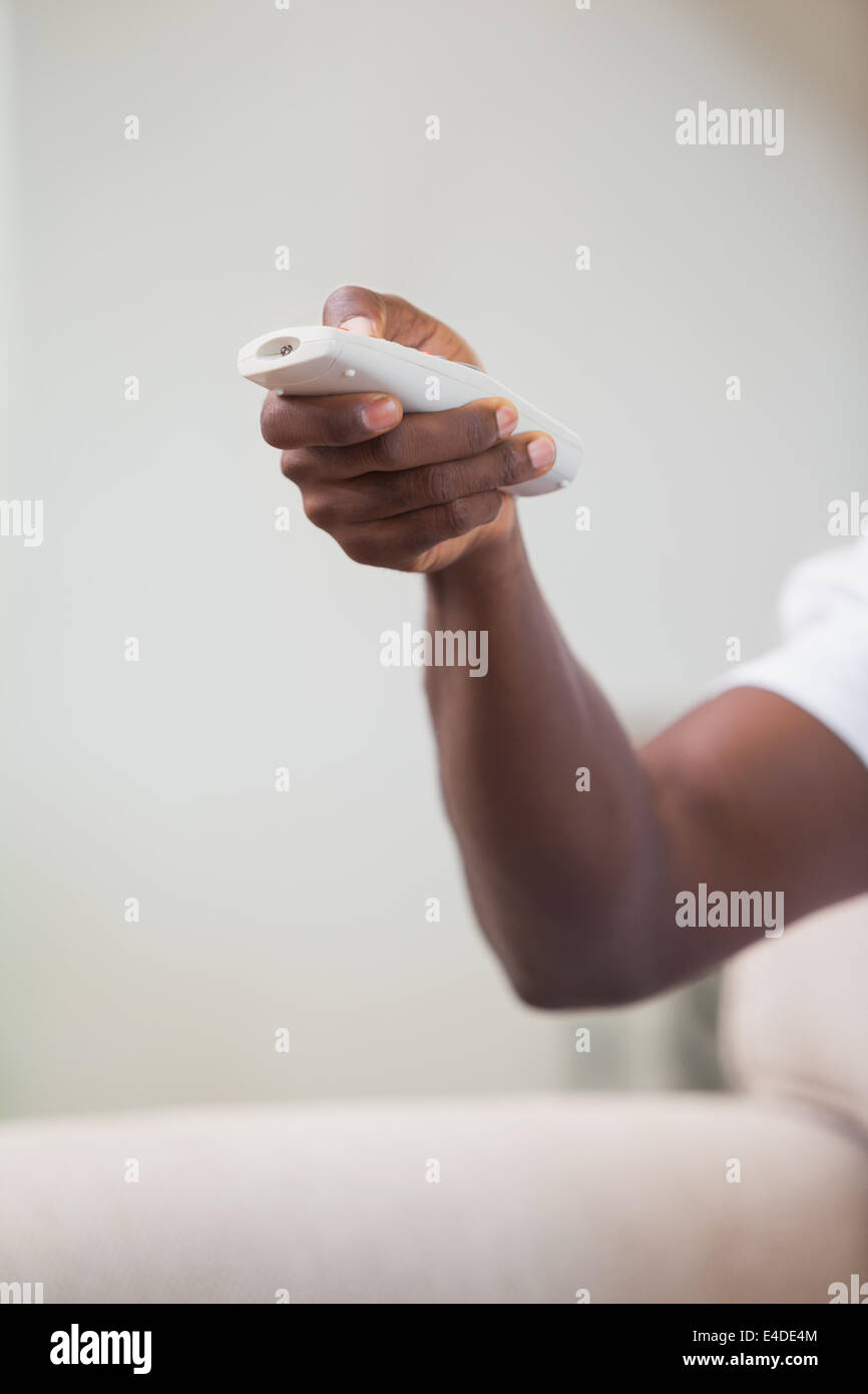 Man holding remote control on couch Stock Photo - Alamy