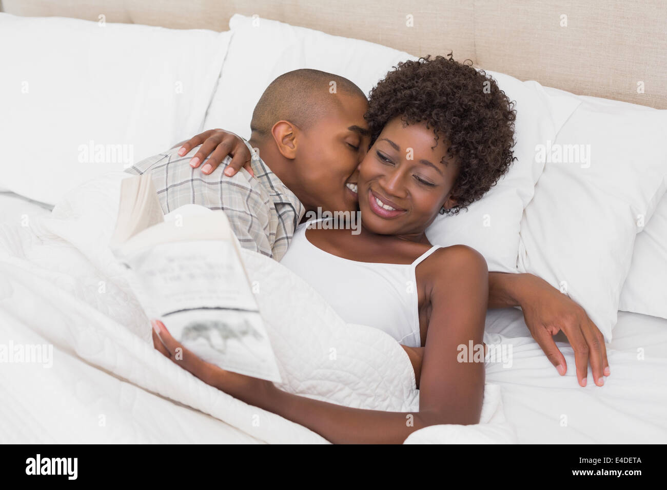 Happy couple lying in bed cuddling Stock Photo - Alamy