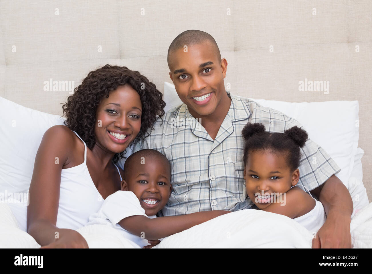 Happy family cuddling in bed together Stock Photo - Alamy