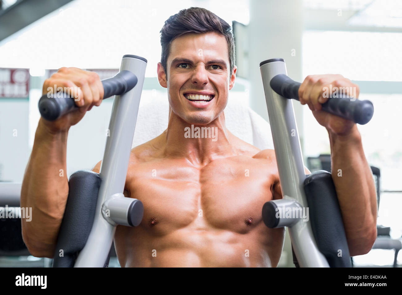 Muscular man working on fitness machine at the gym Stock Photo - Alamy