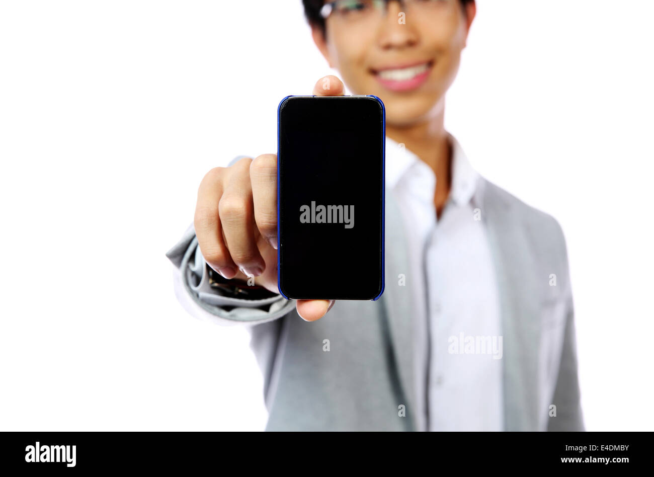 Smiling asian man holding smartphone over white background. Focus on ...