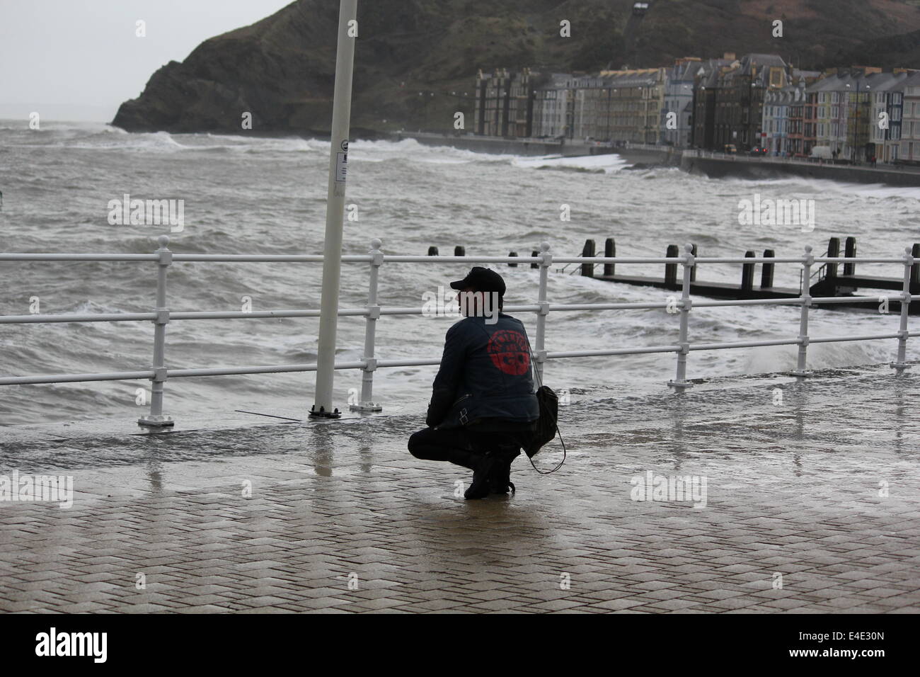A punk style man posing on Aberystwyth promenade in front of stormy ...