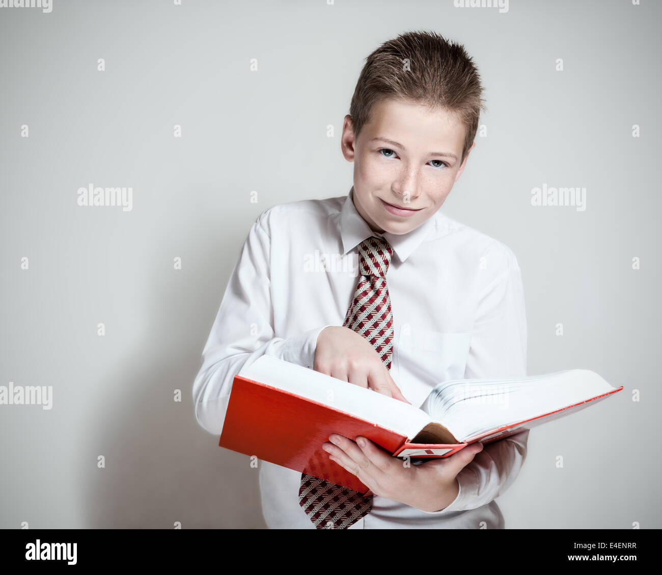 The nice smiling boy reads a big red book on a gray background Stock ...
