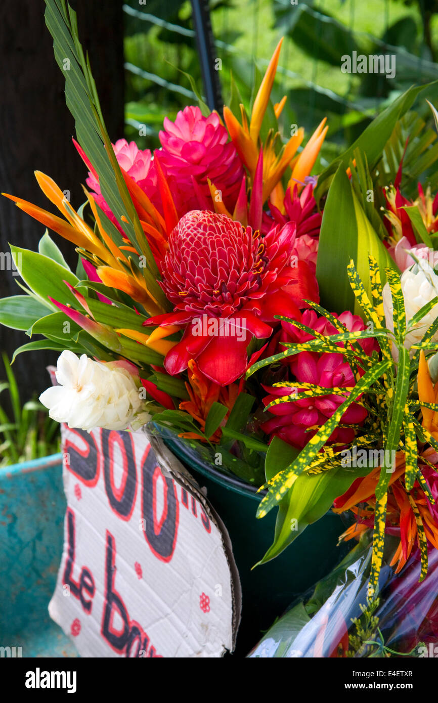A bouquet of tropical flowers being sold at a self serve stand on ...