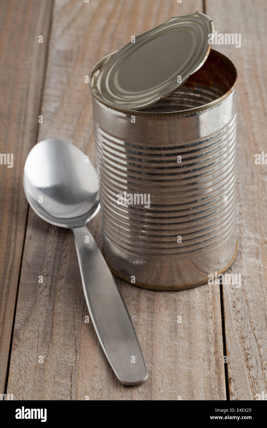 Empty canned food tin with spoon on wooden table - unhealthy eating ...