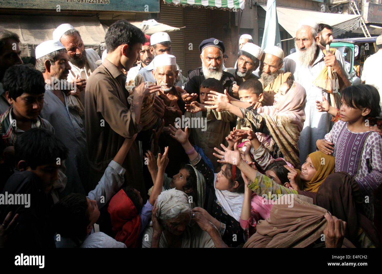 Peshawar, Pakistan. 10th July, 2014. A man distributes donated food ...