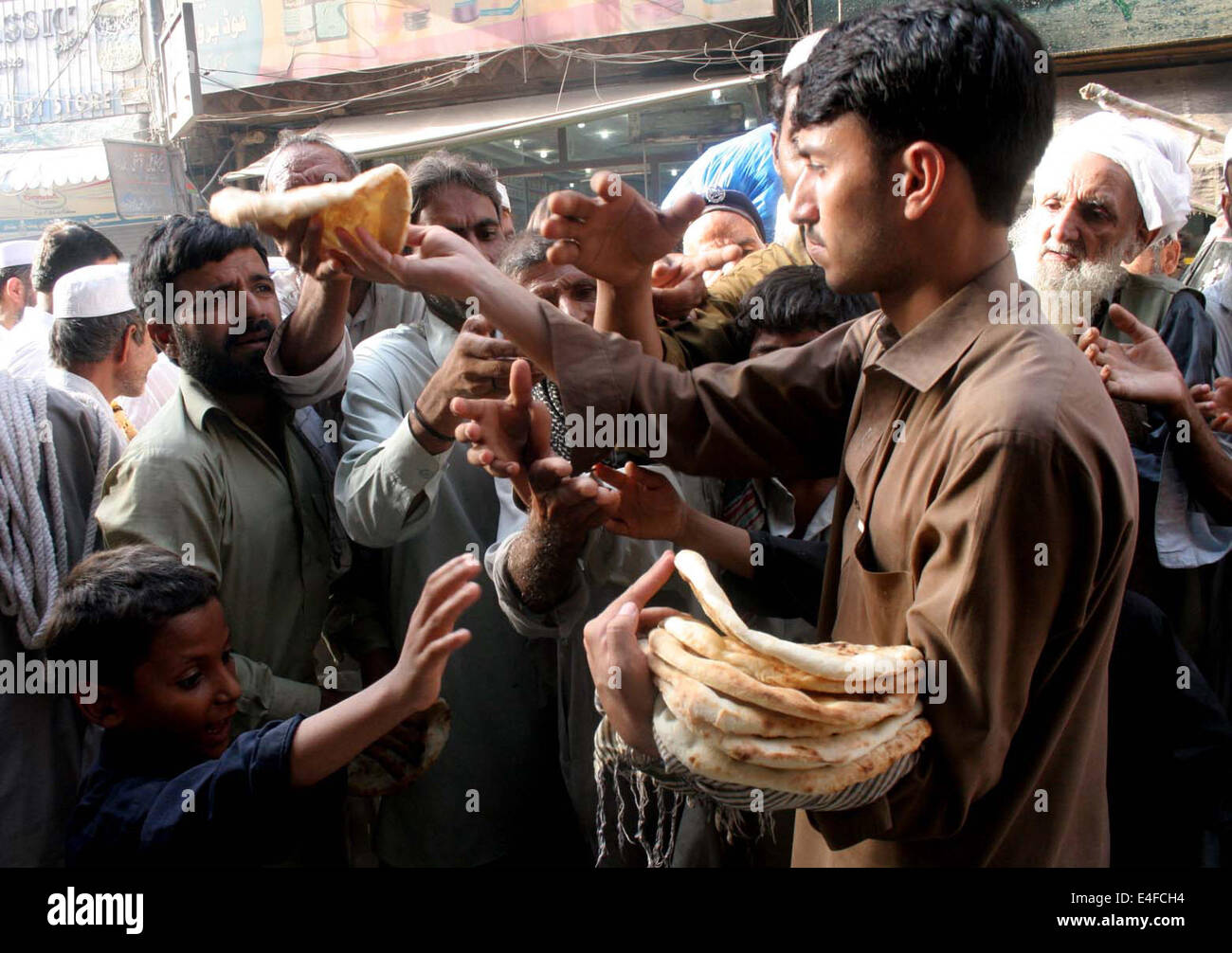 Peshawar, Pakistan. 10th July, 2014. A man distributes donated food ...