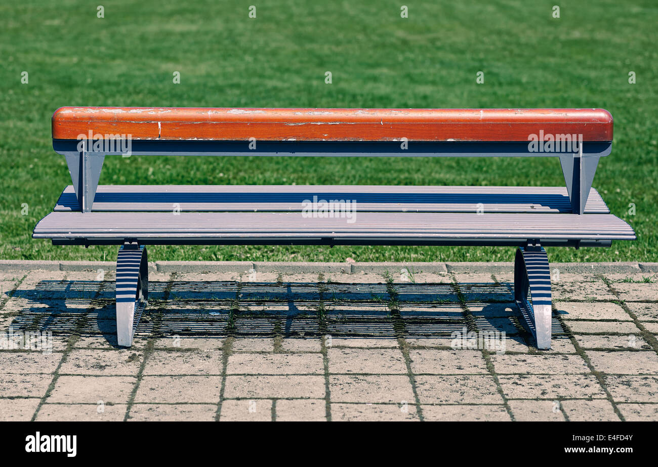 Empty metallic bench with a wooden seat back, cross processed image ...