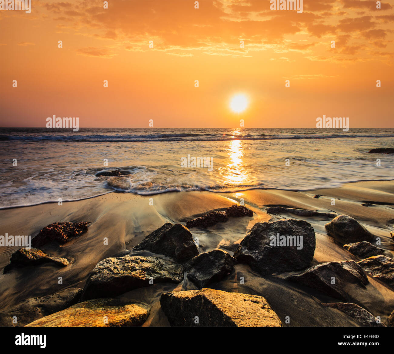 Tropical beach vacation background - waves and rocks on beach on sunset ...