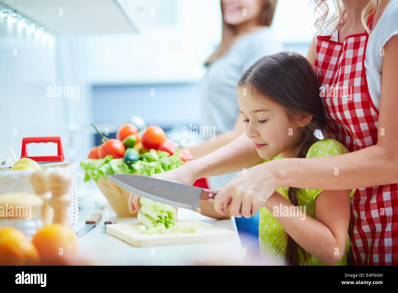 Portrait of little girl helping her mother to cook in the kitchen Stock ...