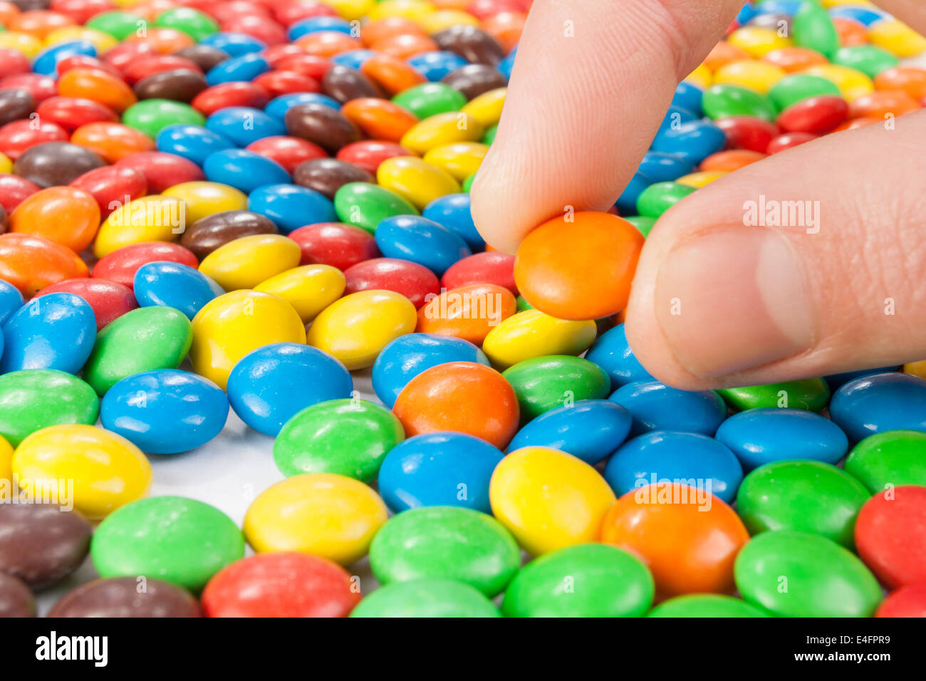Hand picking up Colorful Chocolate Candy background Stock Photo - Alamy