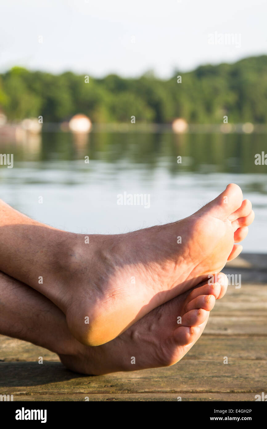A man's feet comfortably rest on the dock at the cottage in the early ...