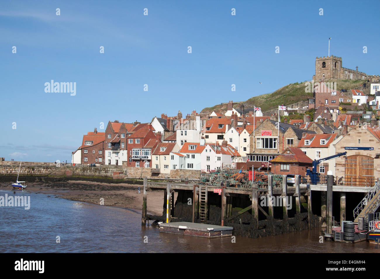View of Whitby harbour and sea wall, with the church on the hill in the ...