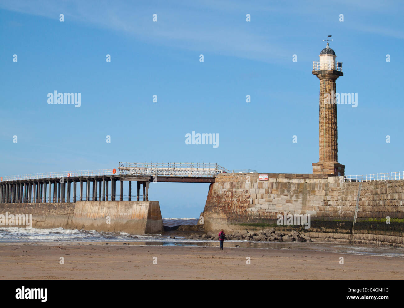 View of Whitby beach, with the sea wall and lighthouse in the ...
