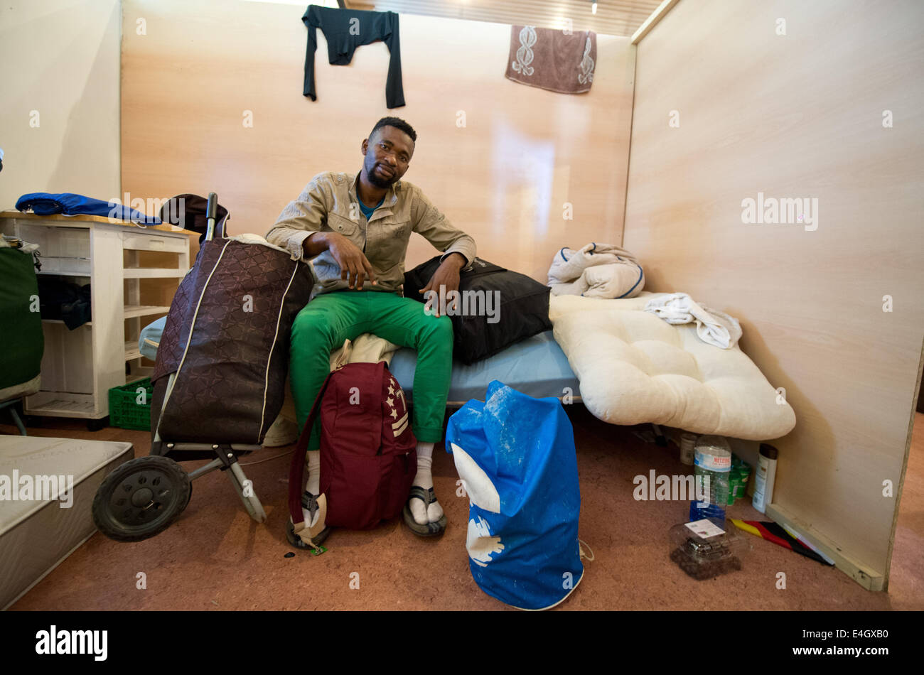 A refugee from Ghana sits with his packed up belongings on a bed on the ...