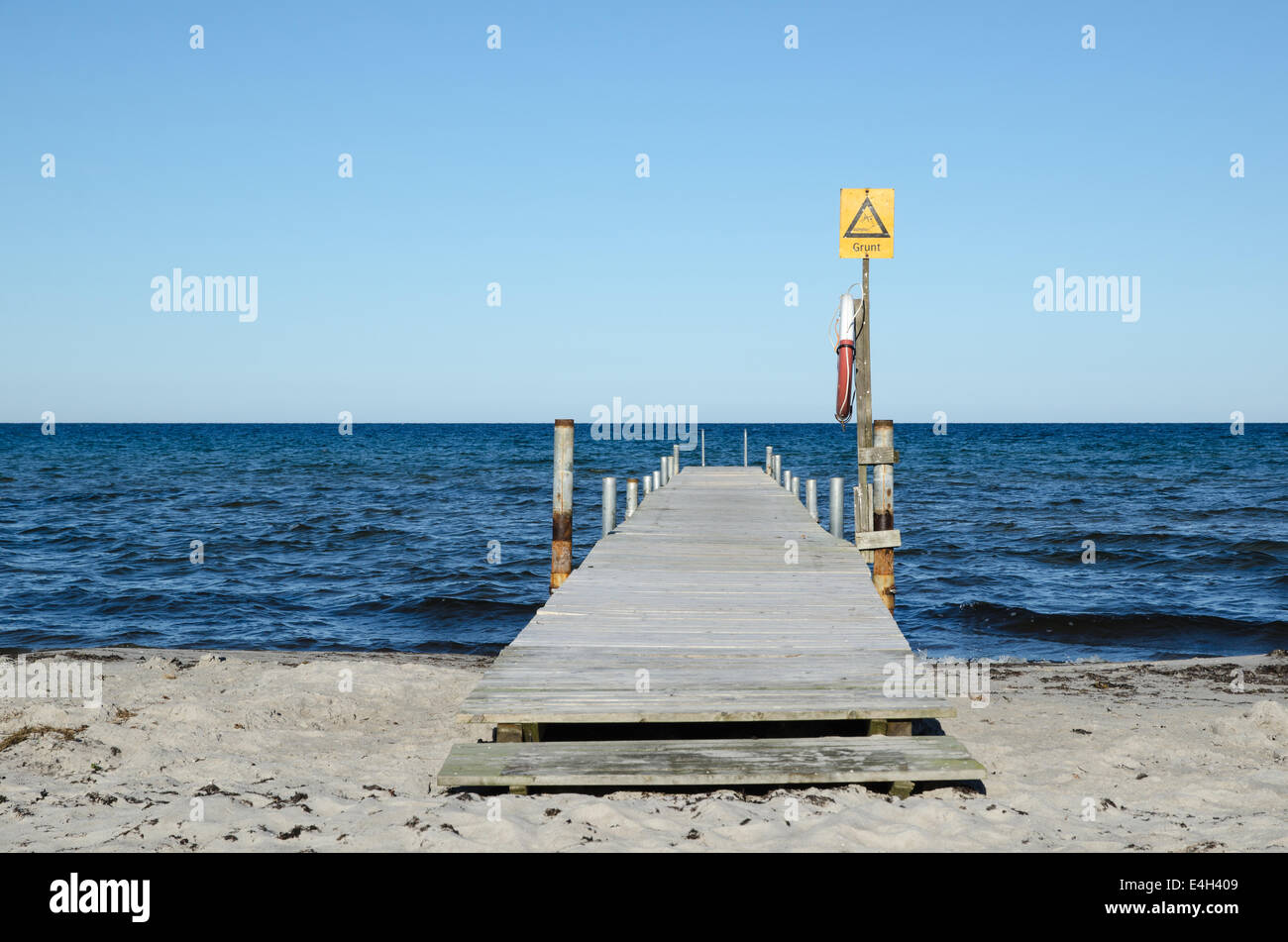 Wooden bath pier with sign for shallow water by the coast of the ...