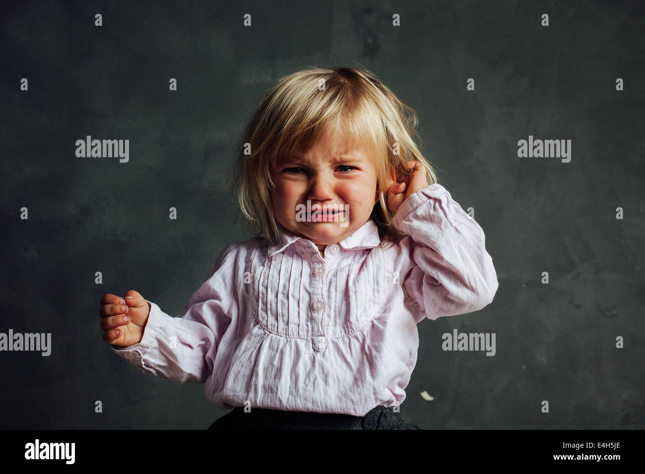 Lifestyle. Portrait of emotional little girl crying on a gray ...