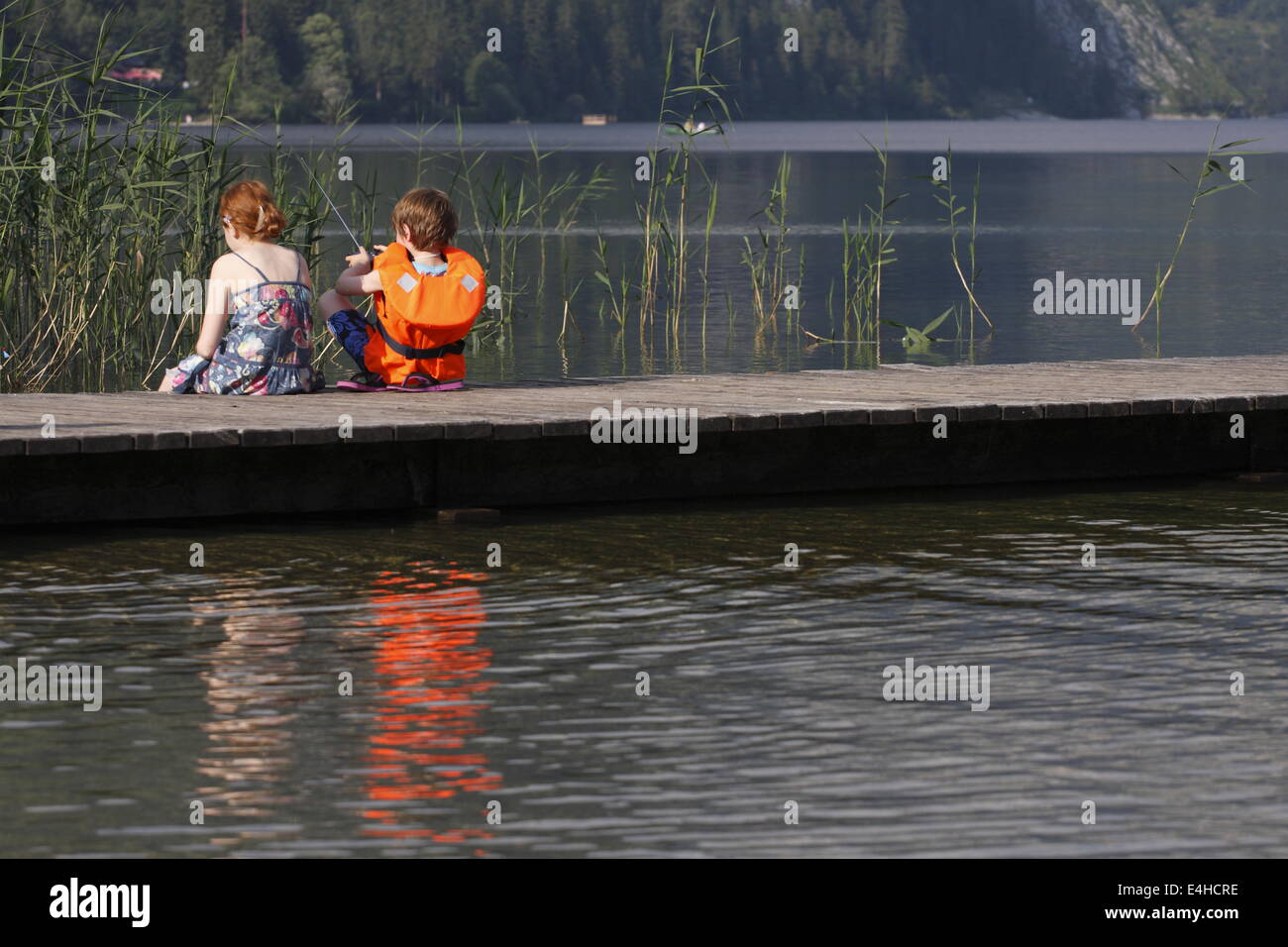 Two children playing with fishing rode on the bridge Stock Photo - Alamy