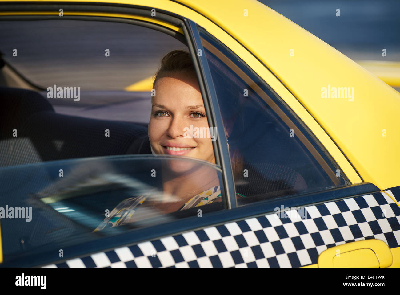 blond woman in yellow taxi looking out of car window and smiling ...
