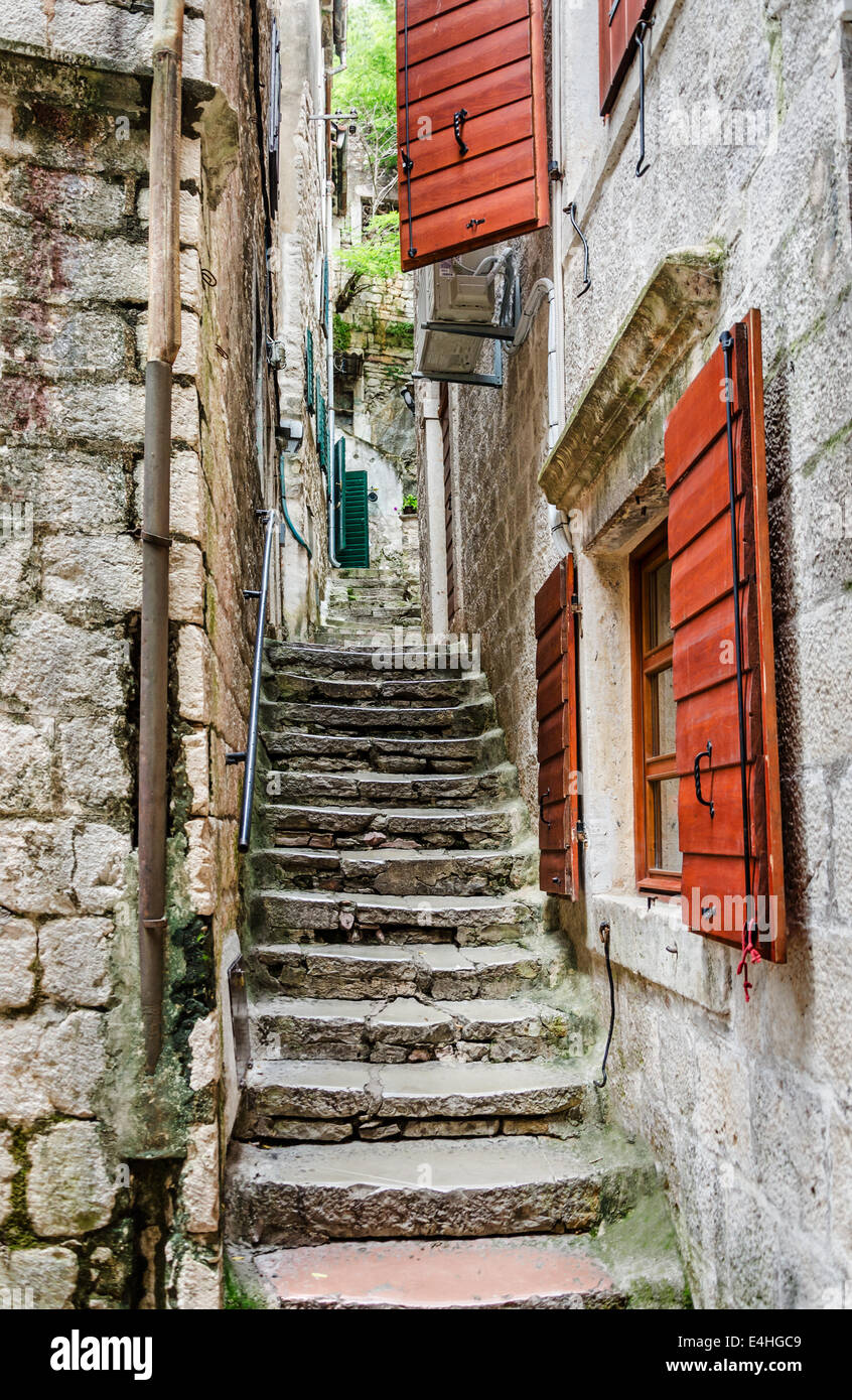 Old stone stairs through a narrow alley with red shutters in the old ...