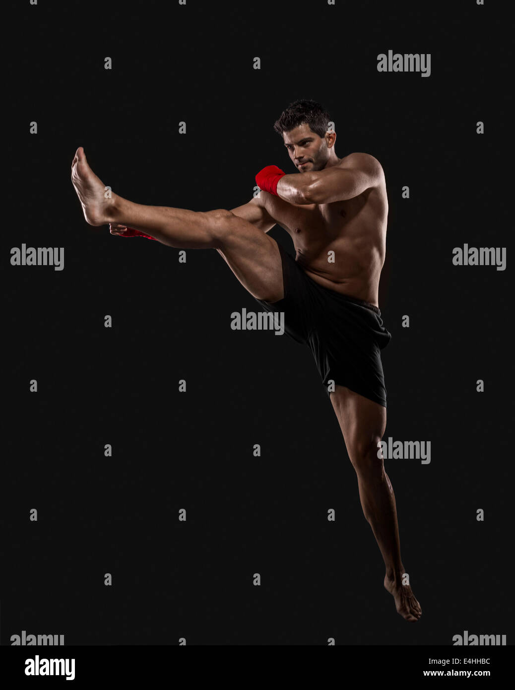 Portrait of a muscular man practicing body combat against a dark ...