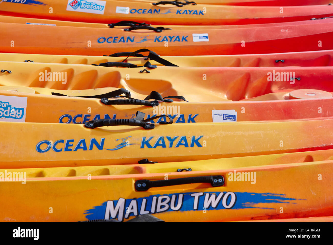 Orange plastic sea kayaks arranged in a row Stock Photo - Alamy