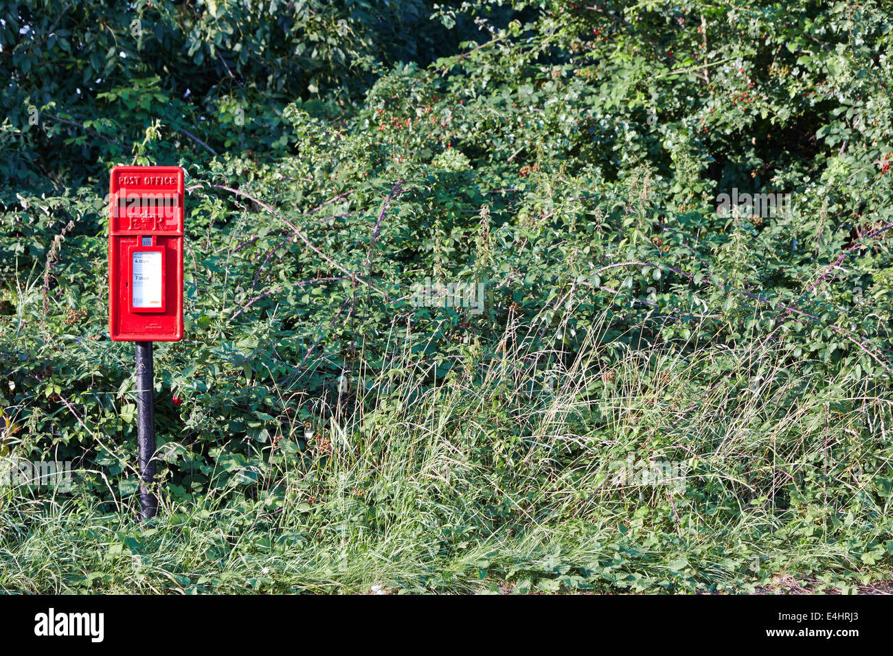 Red old style post box against a green background Stock Photo - Alamy