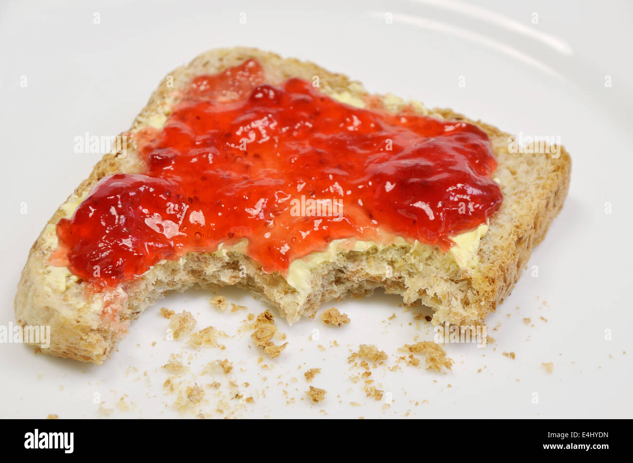 toast sandwich with strawberry jam and butter, missing bite, on white ...