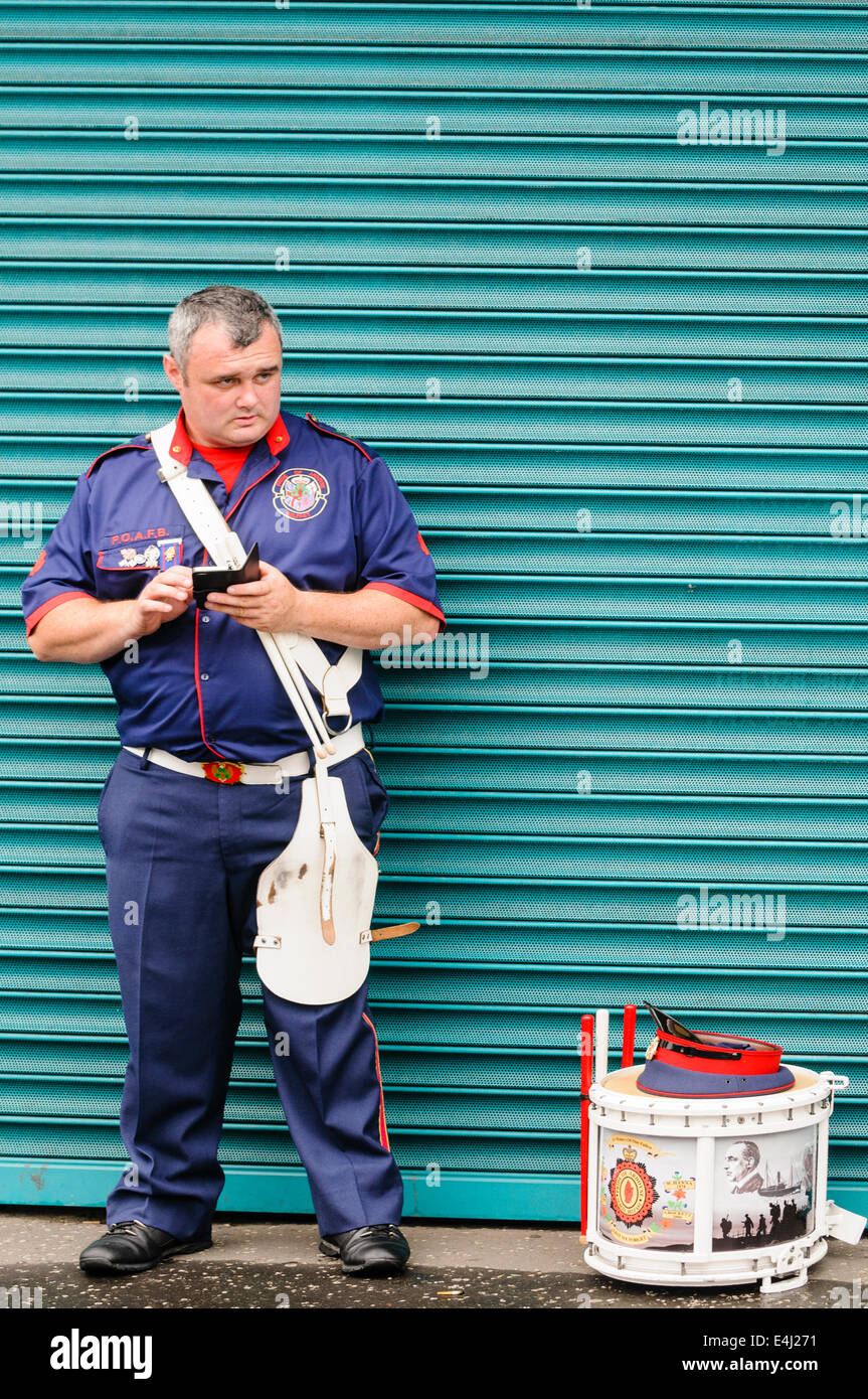 An Orange Bandsman uses his mobile phone while waiting for the parade ...